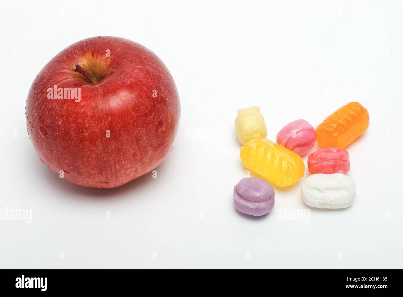 Whole red apple with water drops and a bunch of multicolored sweet ...