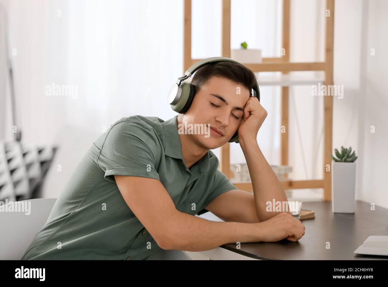 Sleepy young man listening to music at home Stock Photo - Alamy