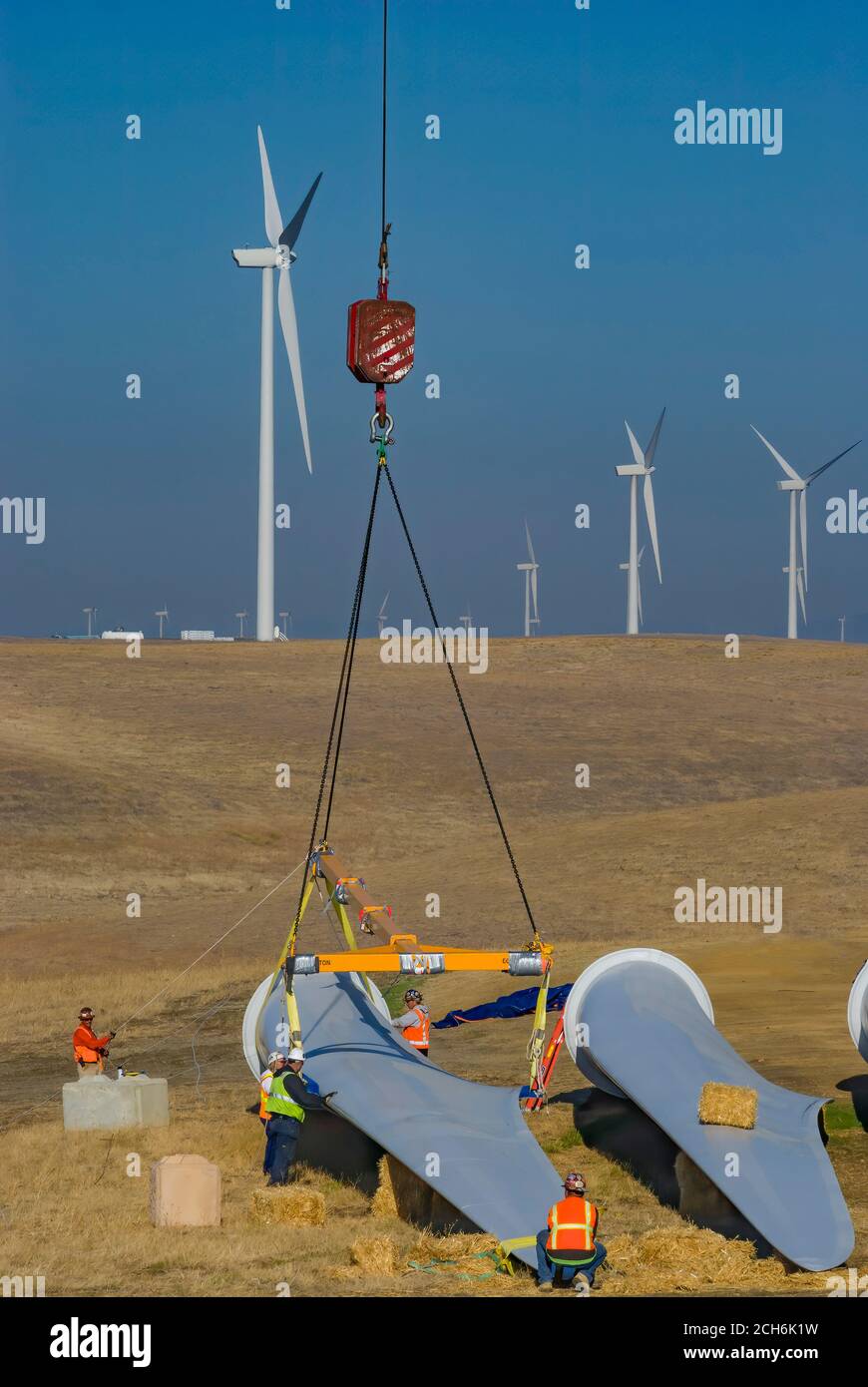 Wind farm construction; technicians preparing one blade to be lifted by ...