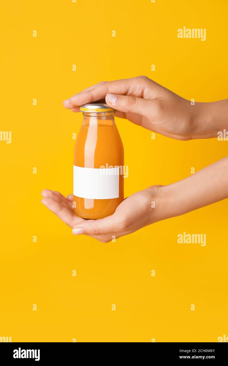 Female hands with bottle of juice on color background Stock Photo - Alamy