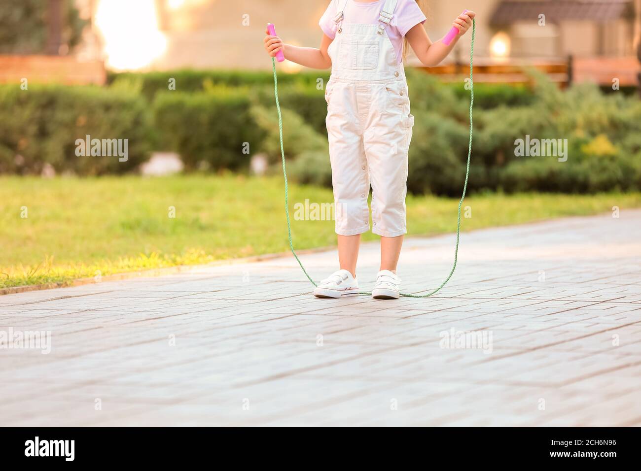 Cute little girl jumping rope outdoors Stock Photo - Alamy