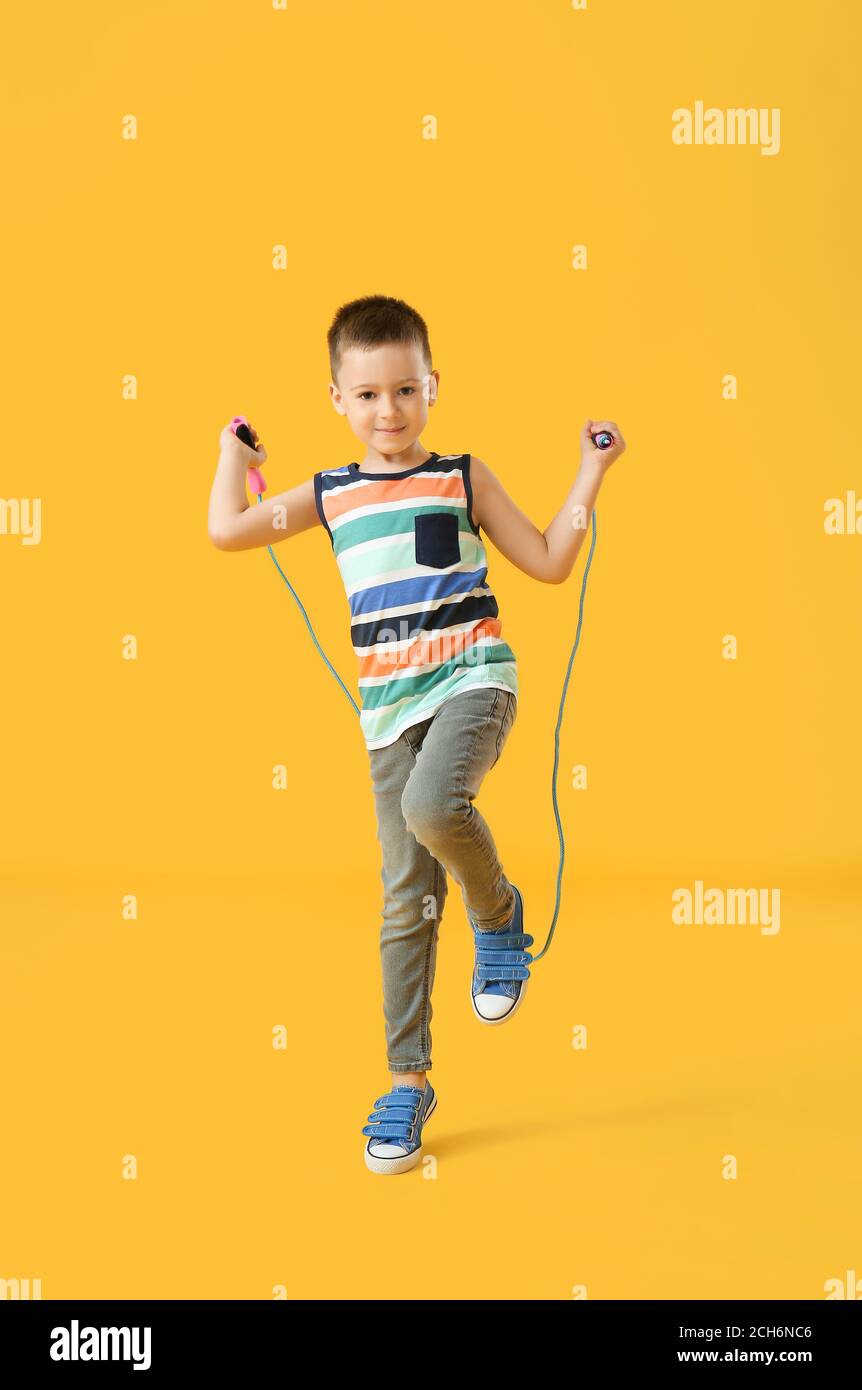 Cute little boy jumping rope against color background Stock Photo - Alamy