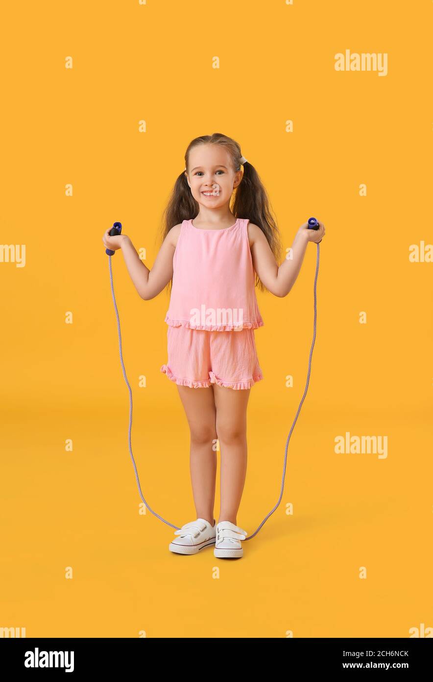 Cute little girl jumping rope against color background Stock Photo - Alamy