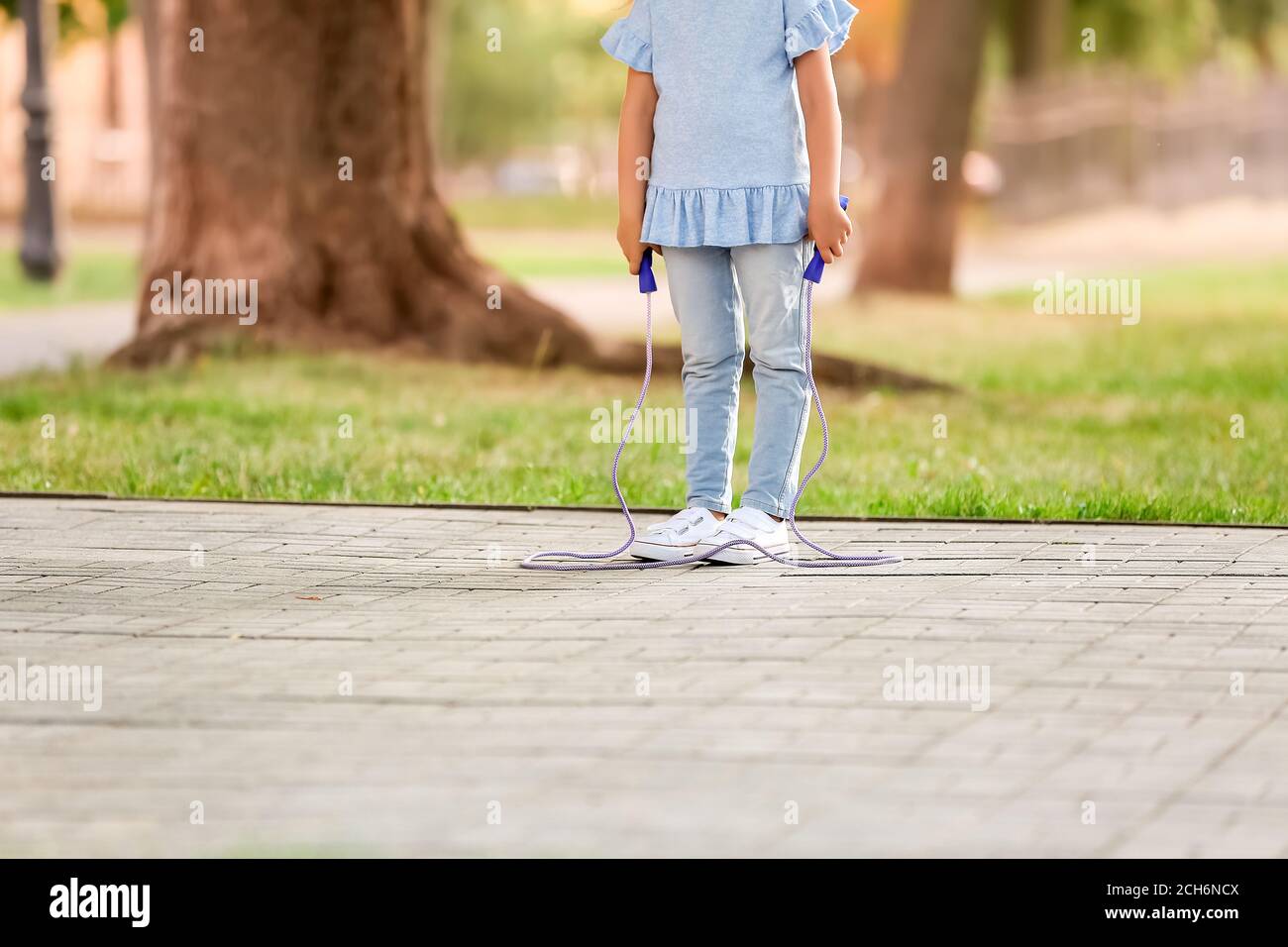 Cute little girl jumping rope outdoors Stock Photo - Alamy