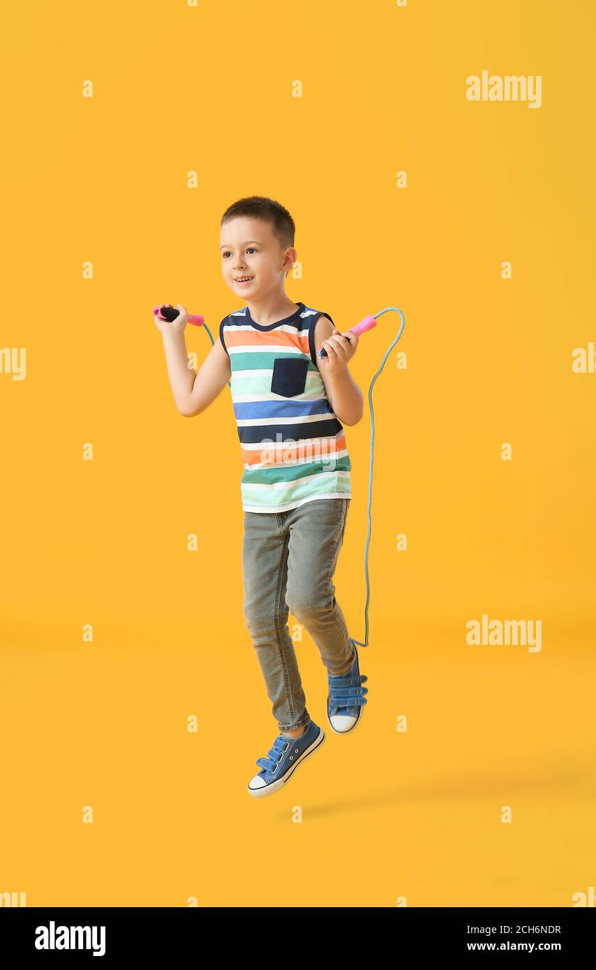 Cute little boy jumping rope against color background Stock Photo - Alamy