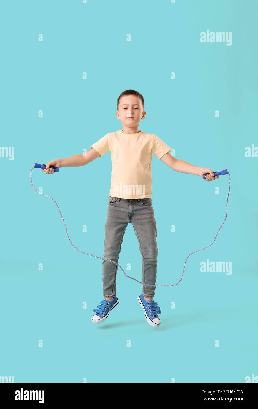 Cute little boy jumping rope against color background Stock Photo - Alamy