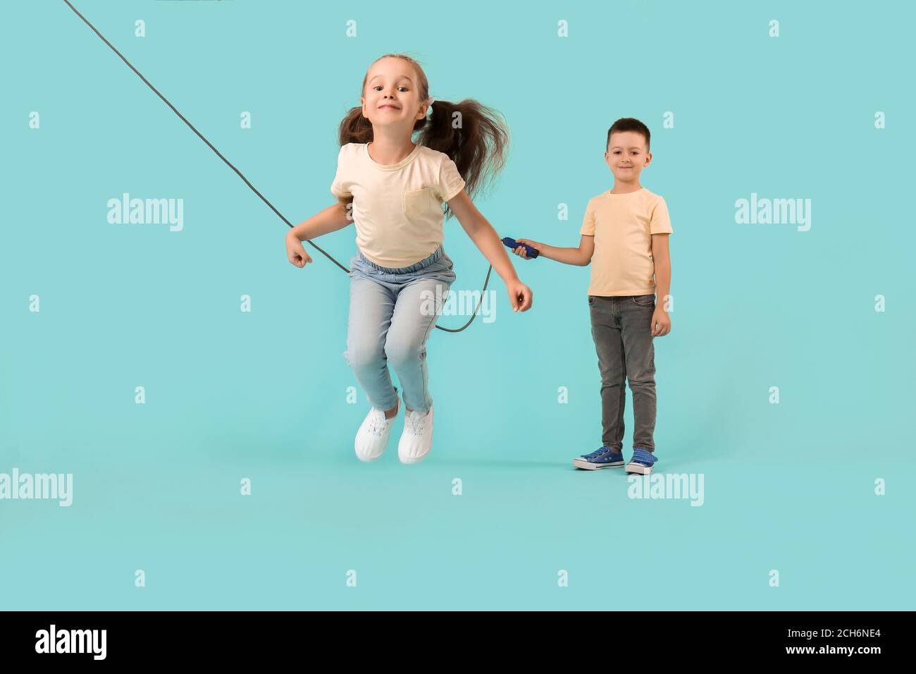 Cute little children jumping rope against color background Stock Photo ...