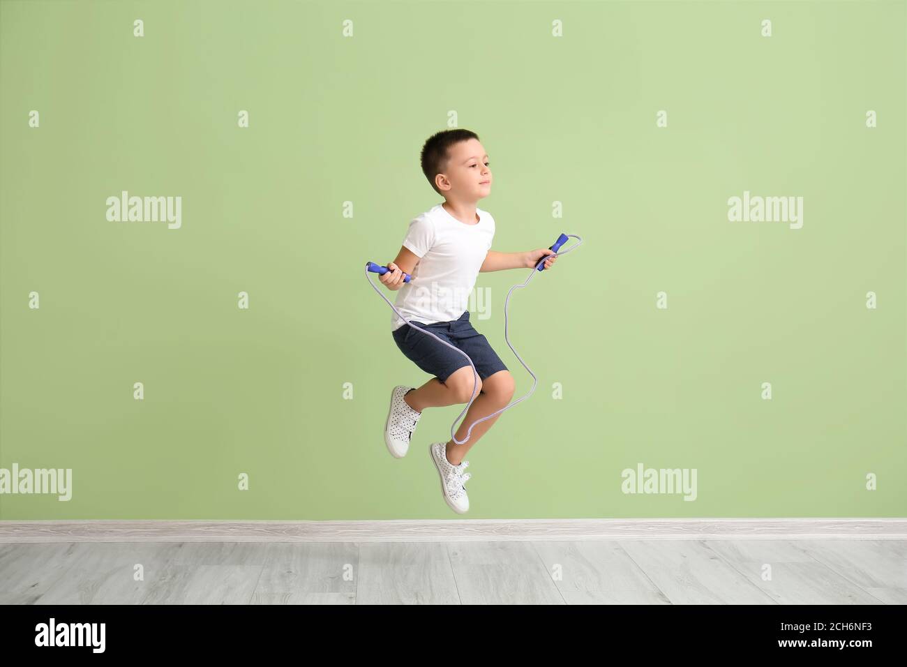 Cute little boy jumping rope near color wall Stock Photo - Alamy