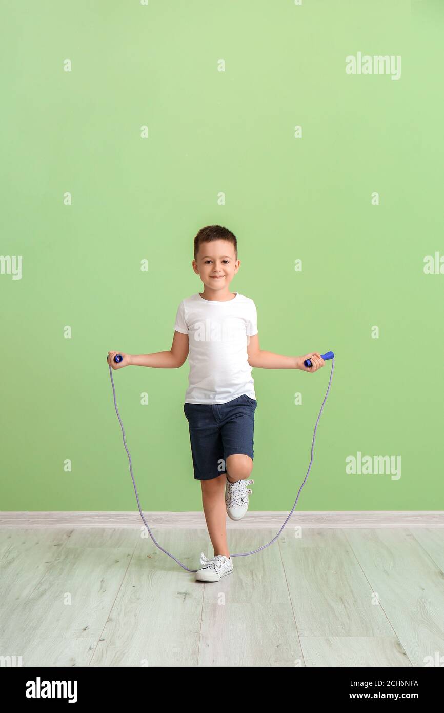 Cute little boy jumping rope near color wall Stock Photo - Alamy