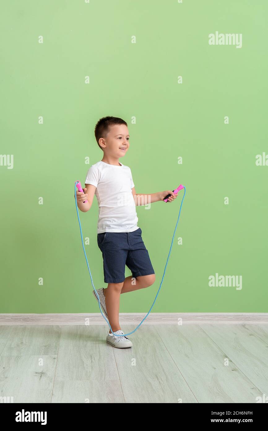 Cute little boy jumping rope near color wall Stock Photo - Alamy