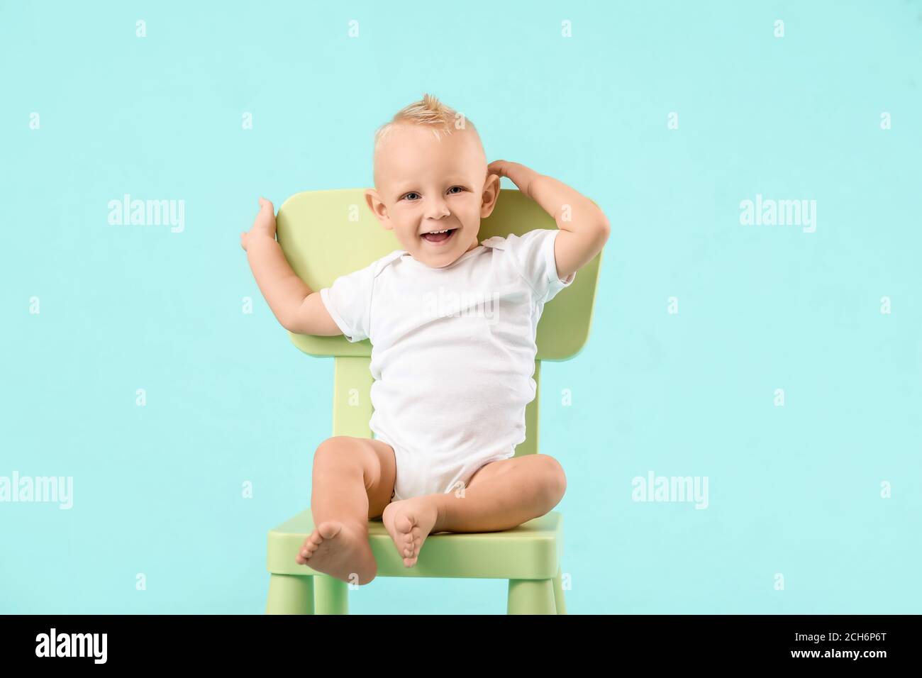 Portrait of cute little baby sitting on chair against color background ...
