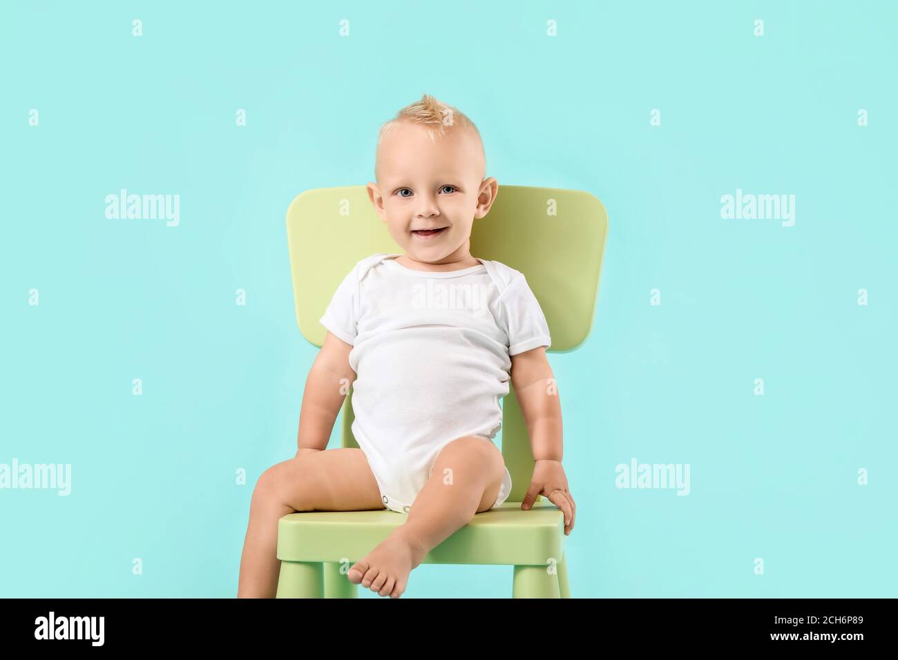 Portrait of cute little baby sitting on chair against color background ...