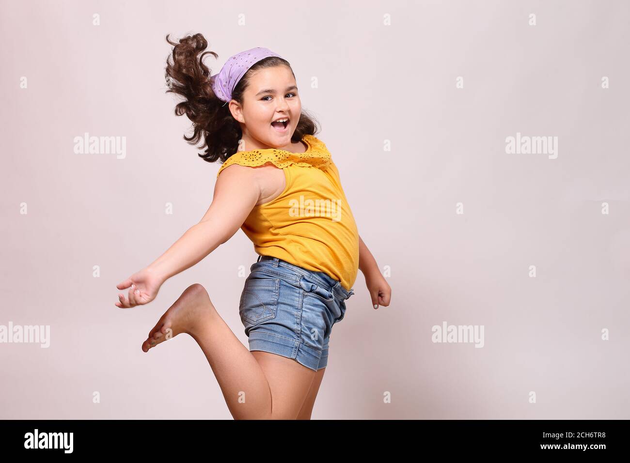 Beautiful portrait of a nine years old girl jumping and smiling on a white background Stock ...