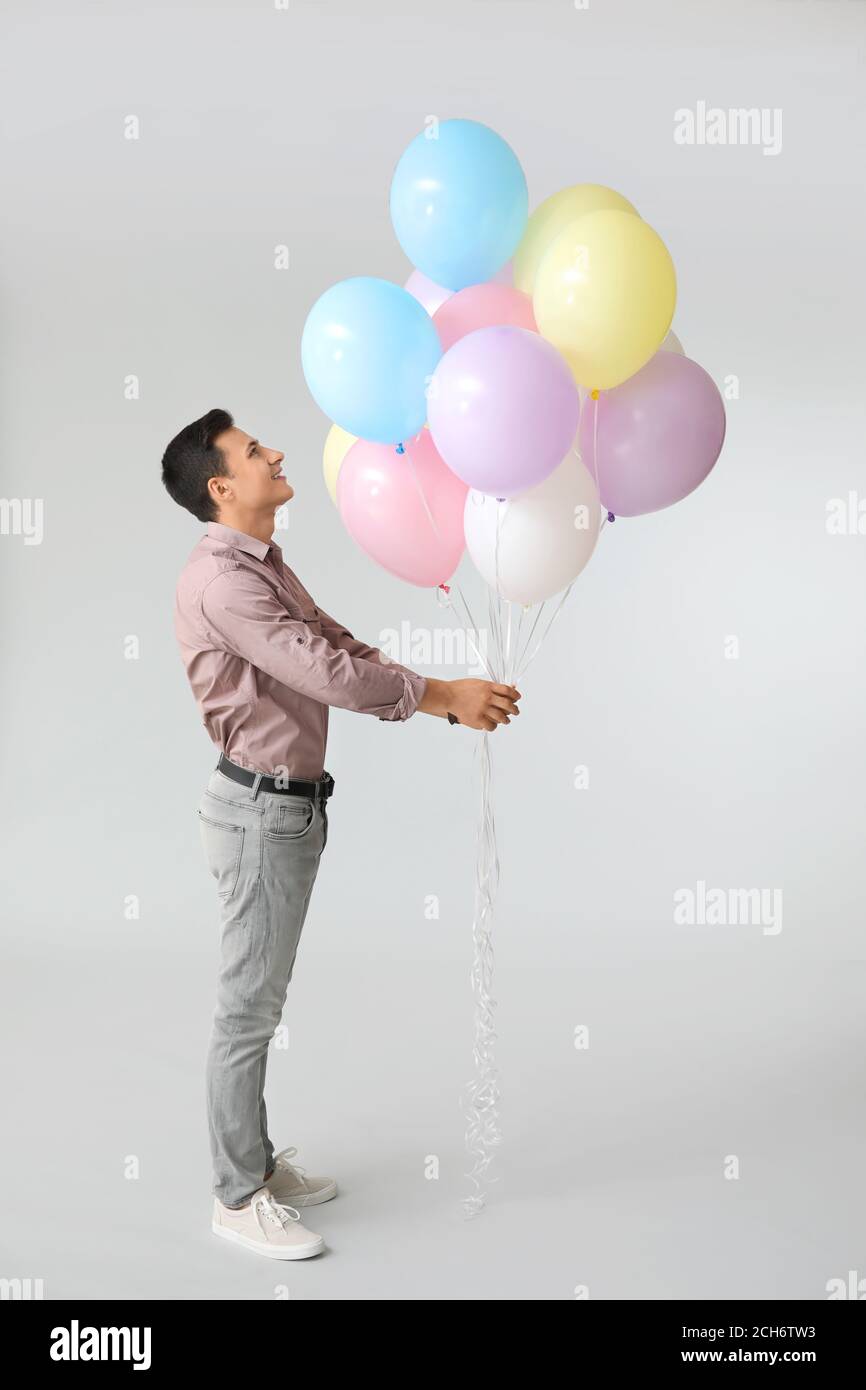 Young man with balloons on grey background Stock Photo - Alamy