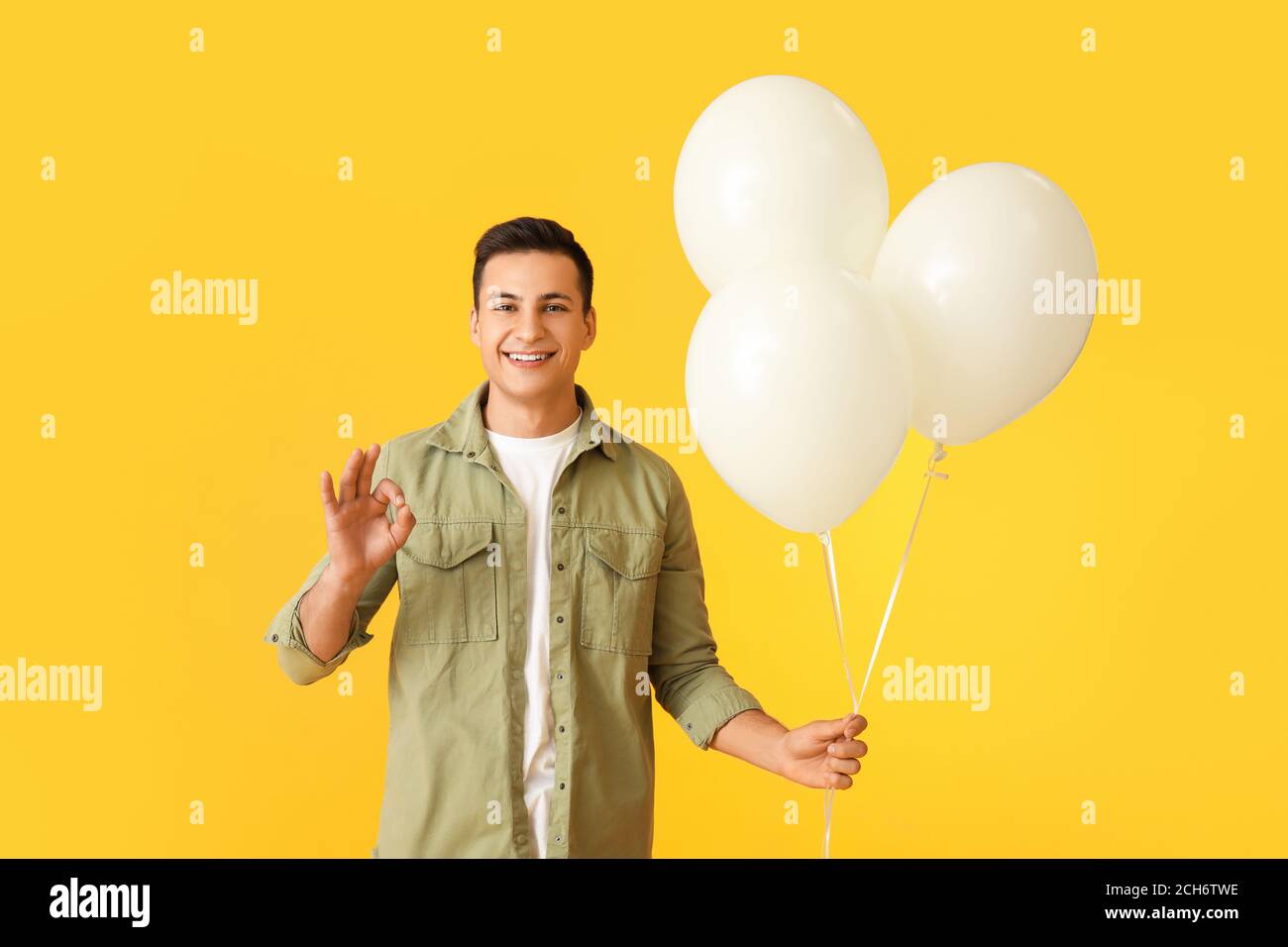 Young man with balloons showing OK on color background Stock Photo - Alamy