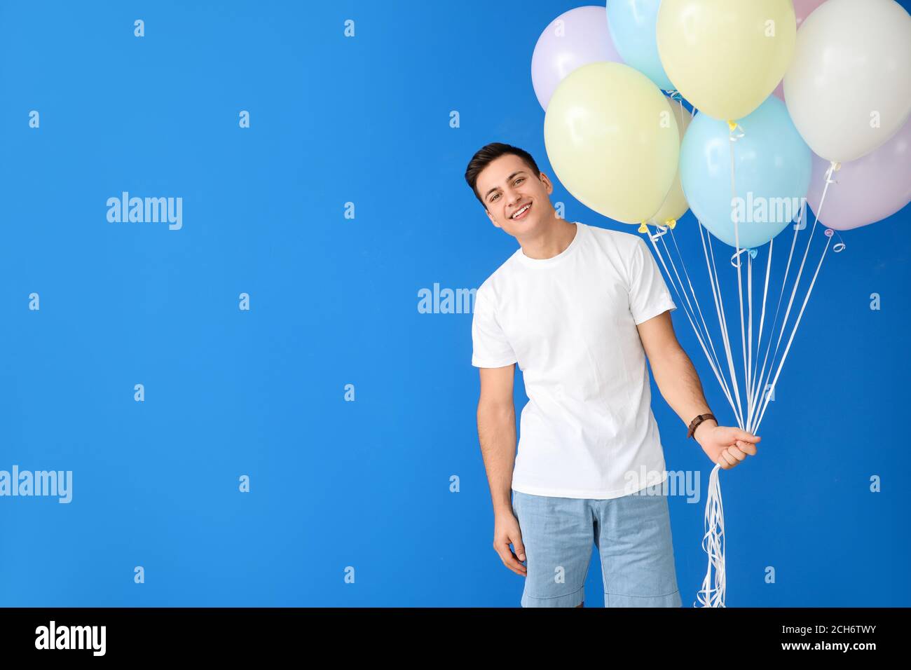 Young man with balloons on color background Stock Photo - Alamy