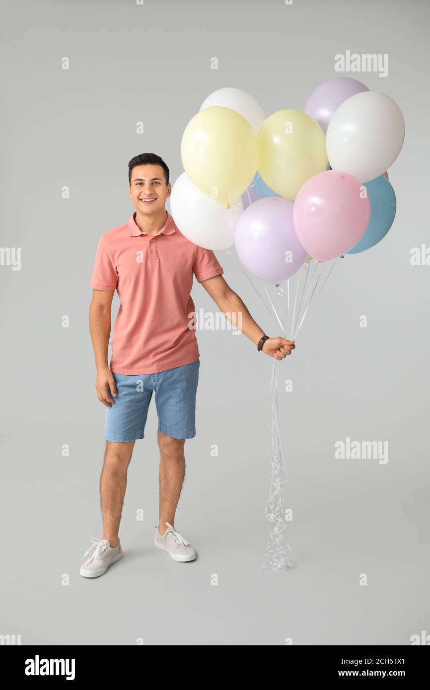Young man with balloons on grey background Stock Photo - Alamy