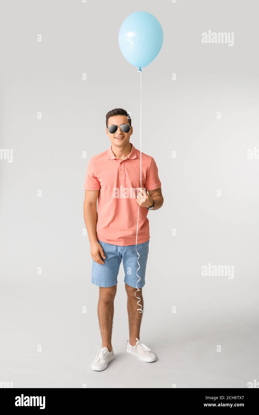 Young man with balloon on grey background Stock Photo - Alamy