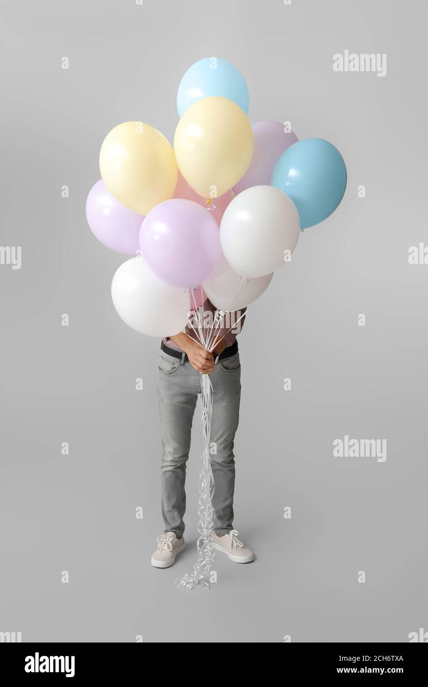 Young man with balloons on grey background Stock Photo - Alamy