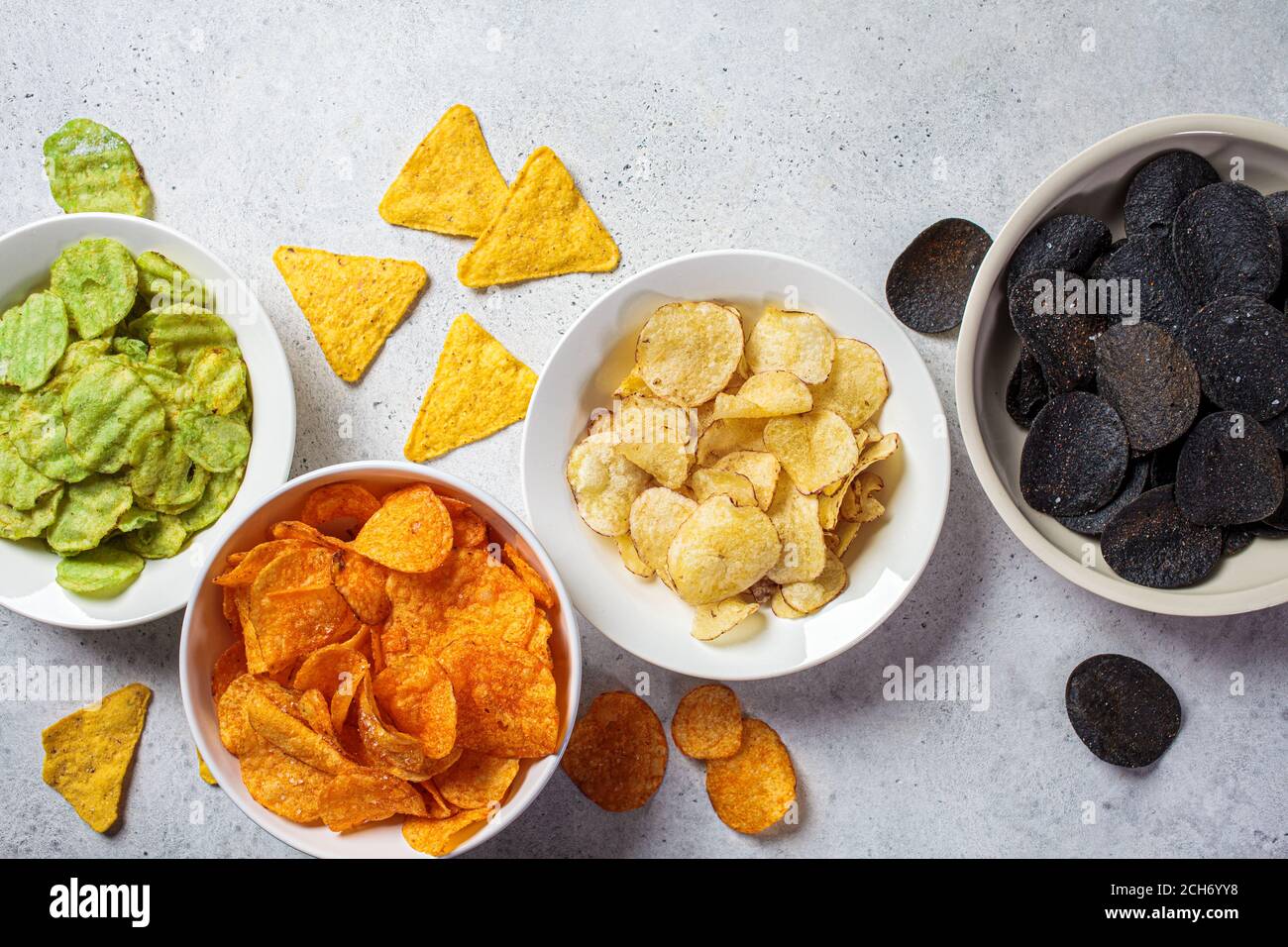 Different types of potato chips in white bowls, gray background. Fast ... Different types of potato chips in white bowls, gray background. Fast ...