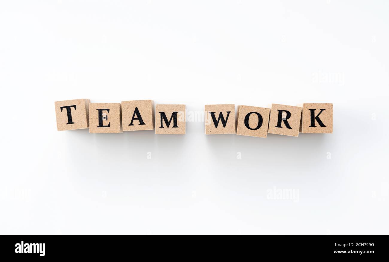 A wooden block with the word TEAM WORK written on it on a white ...