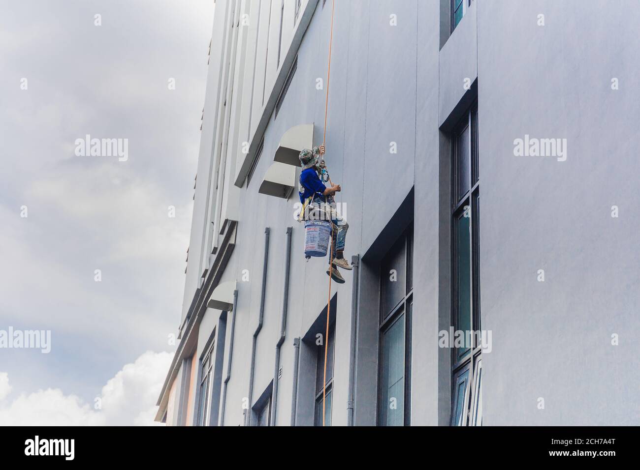 Painter coming down the facade of a building tower rappelling with a ...