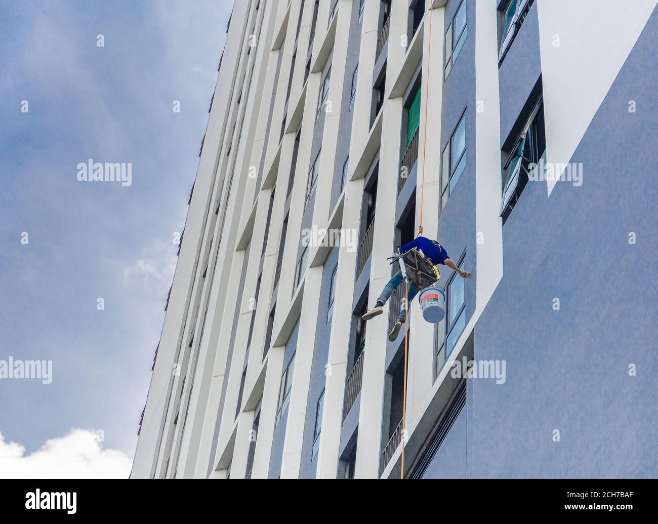 Painter coming down the facade of a building tower rappelling with a ...