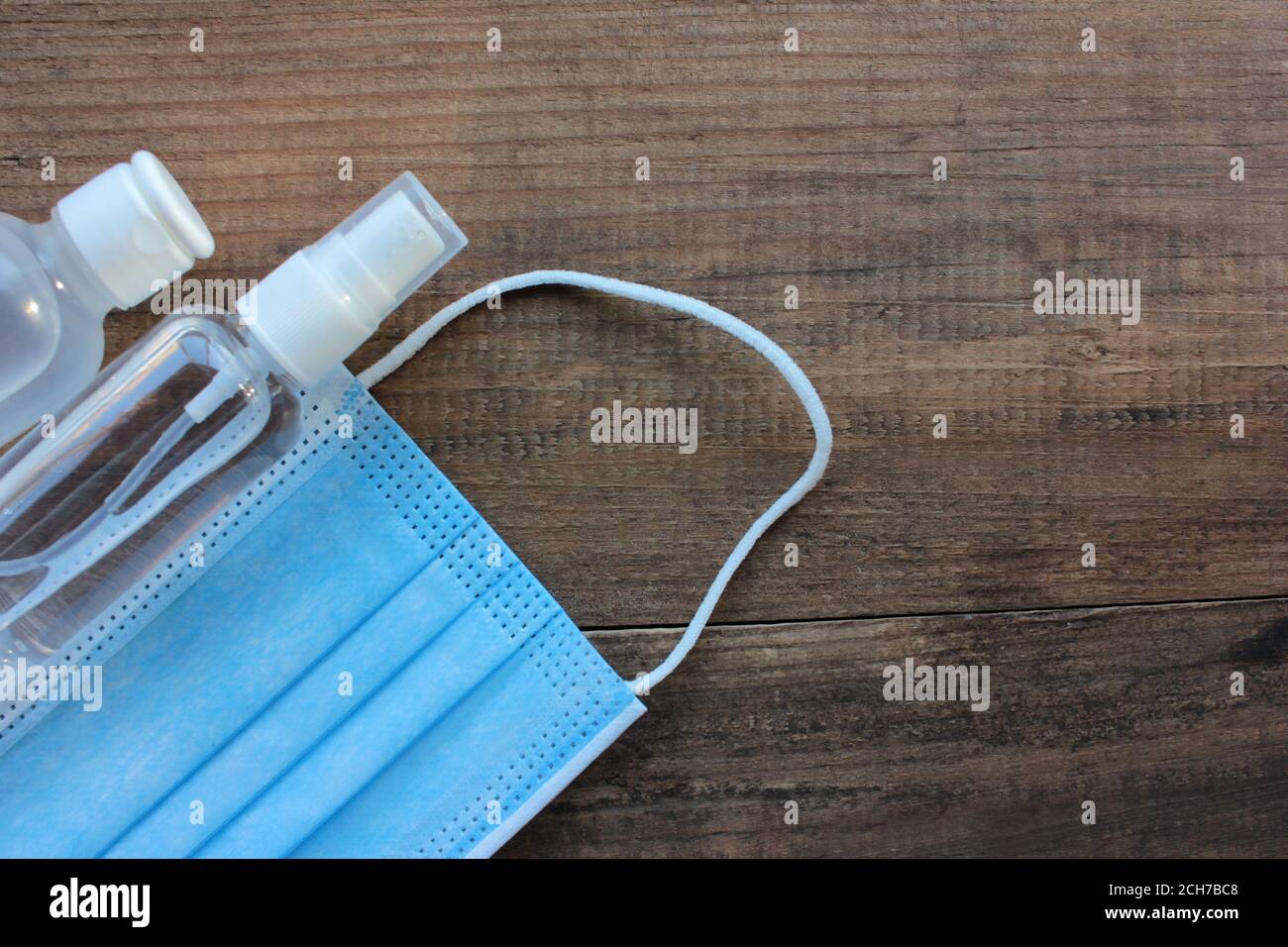 Disposable medical face mask and hand sanitizer bottles on wooden table ...