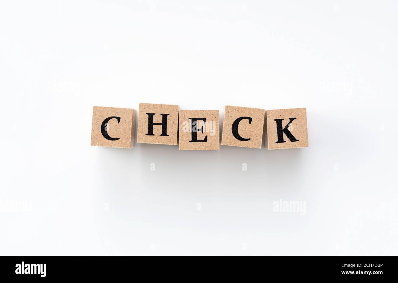 A wooden block with the word CHECK written on it on a white background ...