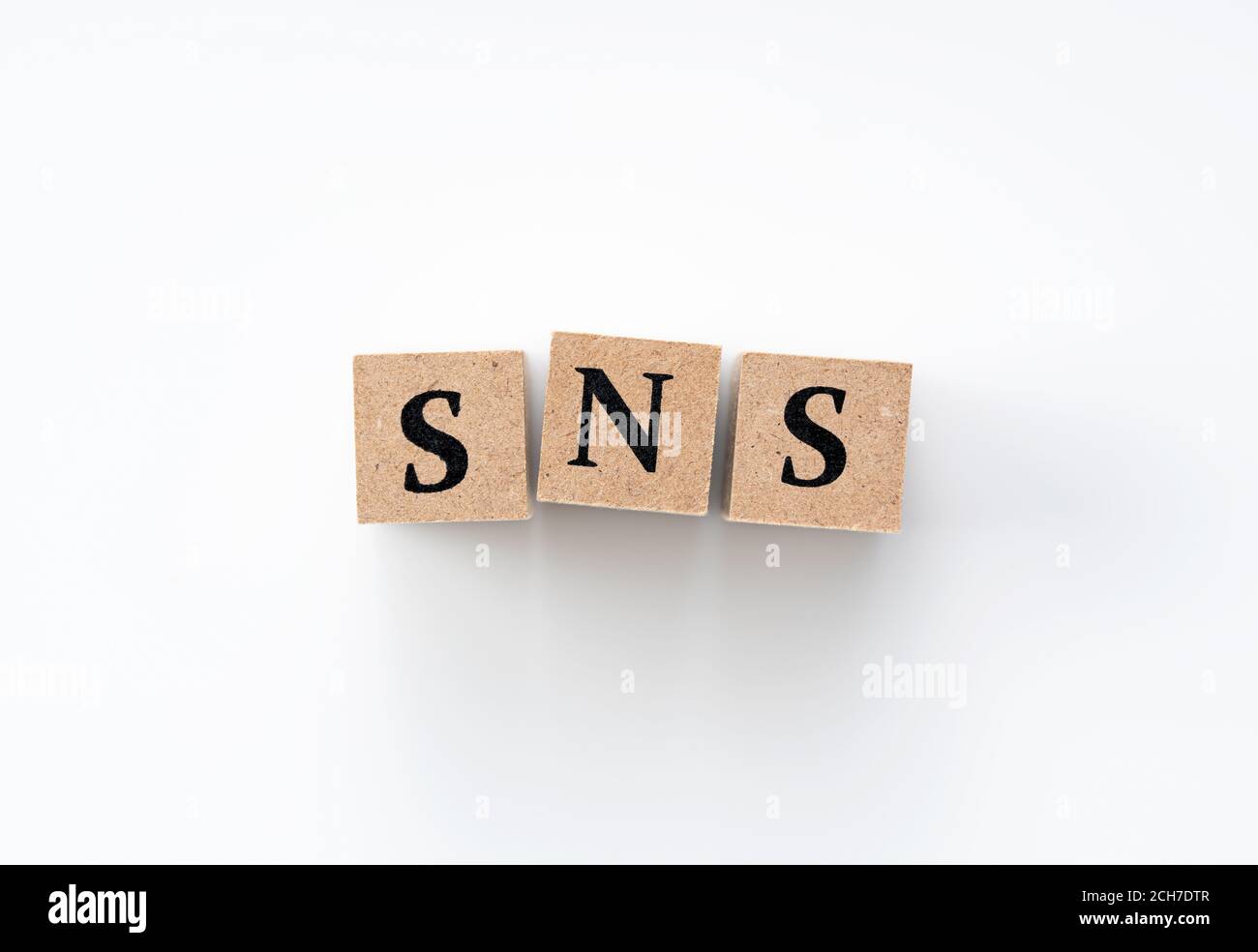 A wooden block with the words SNS written on it on a white background ...