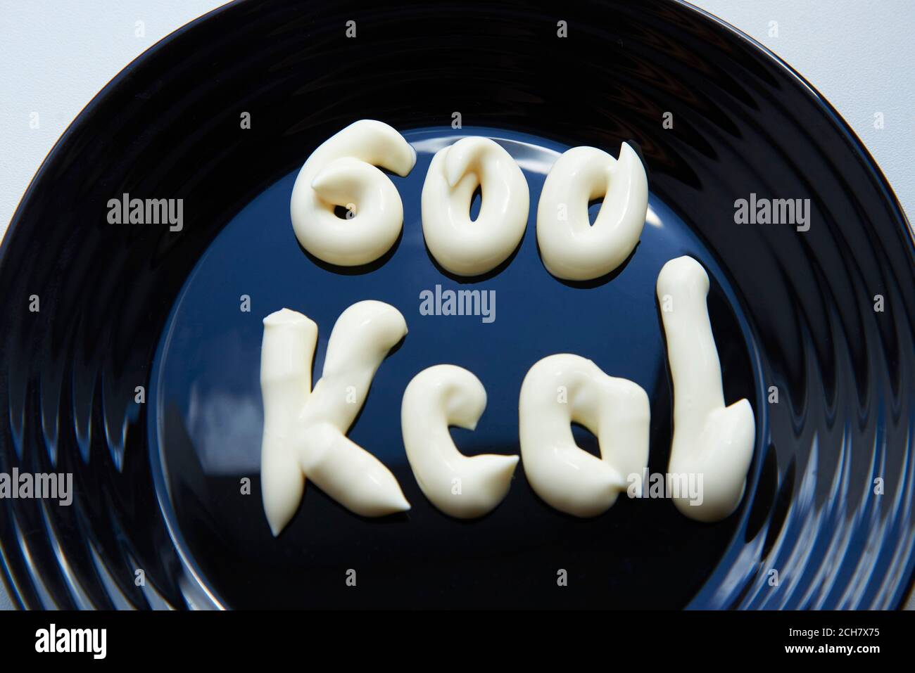 The word 600 Kcal written by mayonnaise on a black plate Stock Photo ...