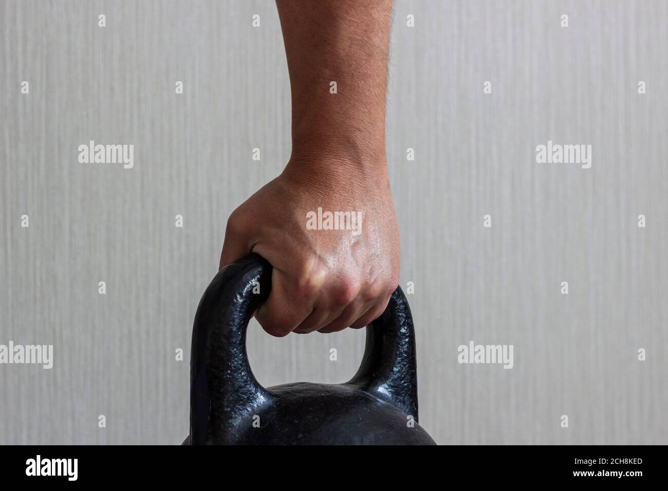 A man's hand firmly holding a cast-iron weight by the handle Stock ...