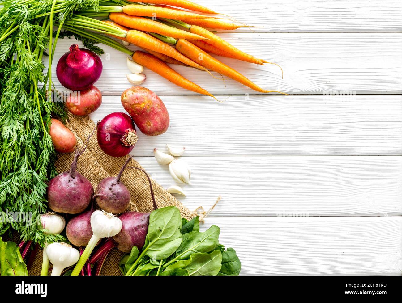 Flat lay of fresh vegetables and greenery on white table top-down copy ...