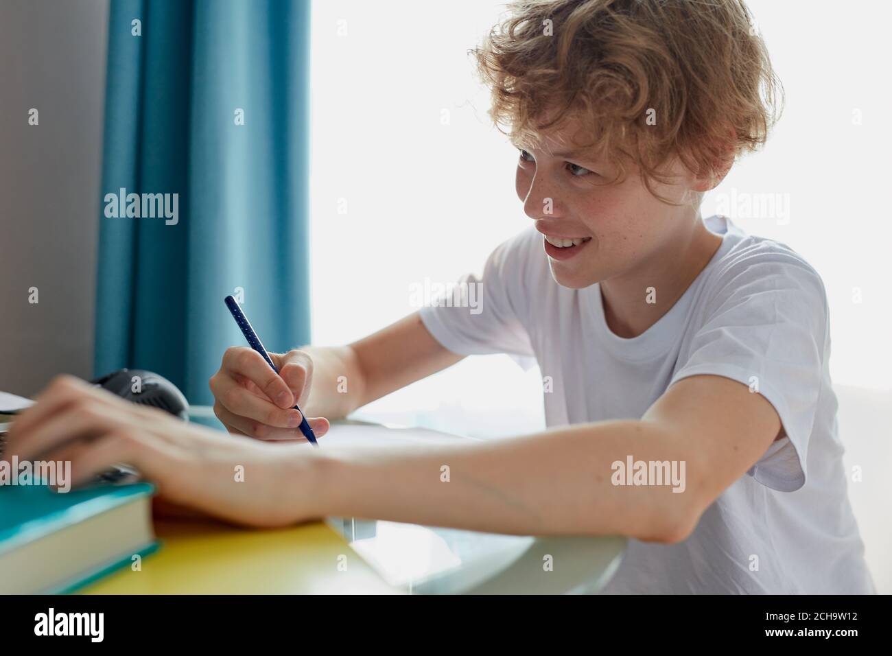 happy child boy doing homework, caucasian curly boy writing on notebook ...