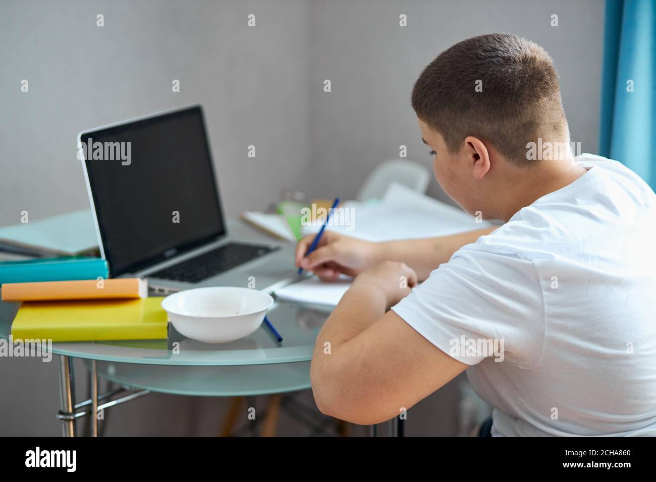 portrait of young caucasian teen boy studying at home, online studying ...