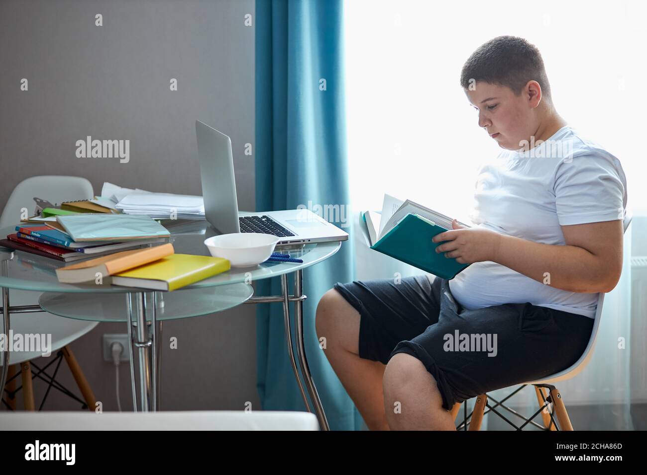 portrait of young caucasian teen boy studying at home, online studying ...