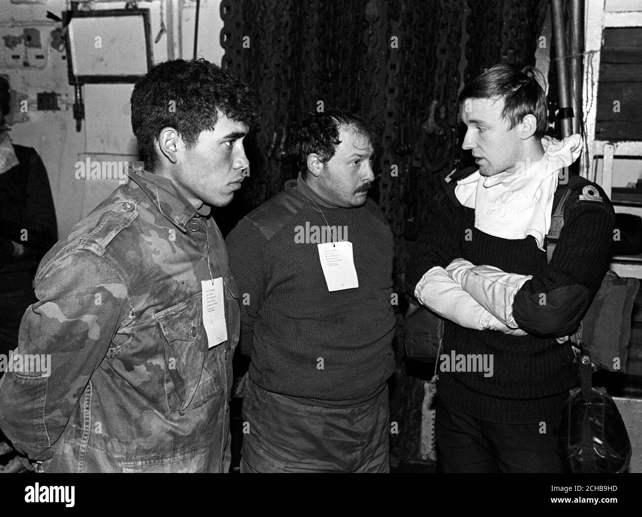 A Royal Navy interpreter talking to two Argentinian prisoners on one of ...