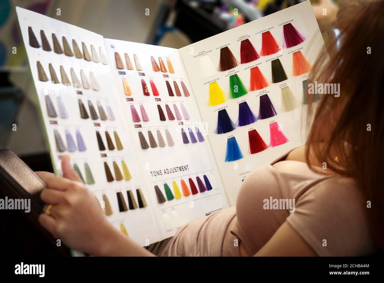 a girl is looking at hair color chart for choosing new color for her ...