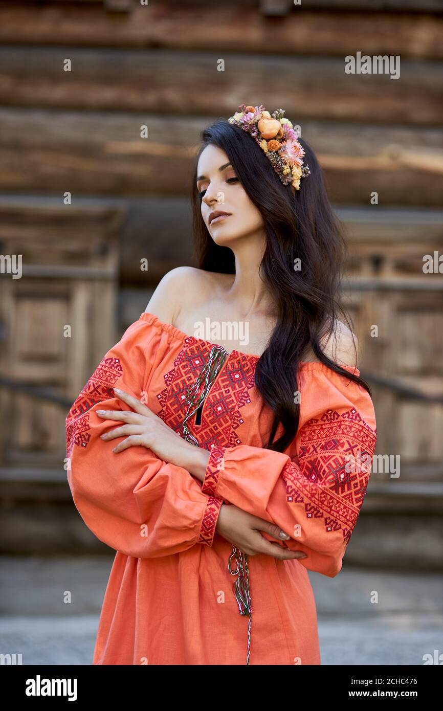 Beautiful Slavic woman in an orange ethnic dress and a wreath of ...