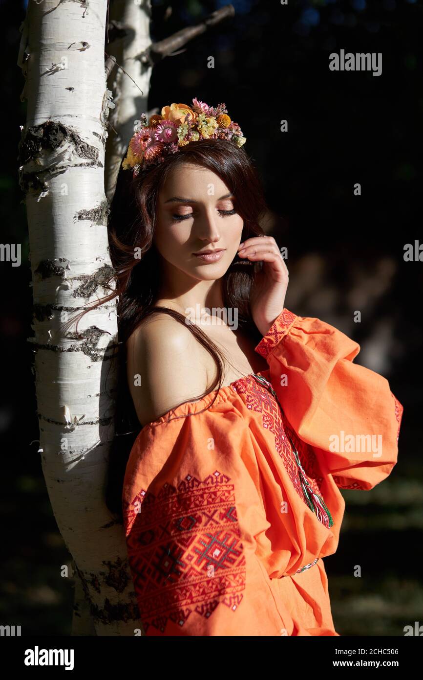 Beautiful Slavic woman in an orange ethnic dress and a wreath of ...