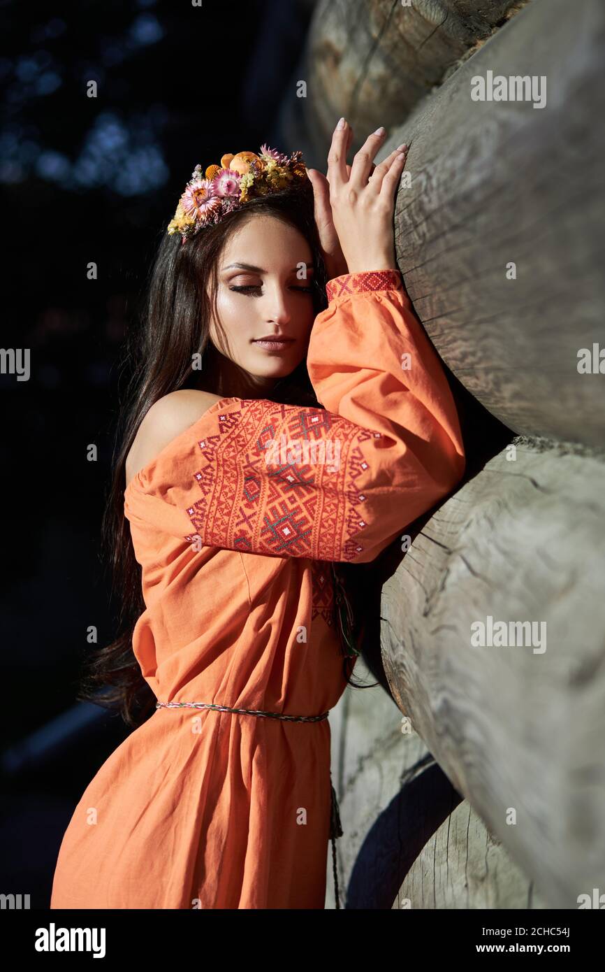 Beautiful Slavic woman in an orange ethnic dress and a wreath of ...