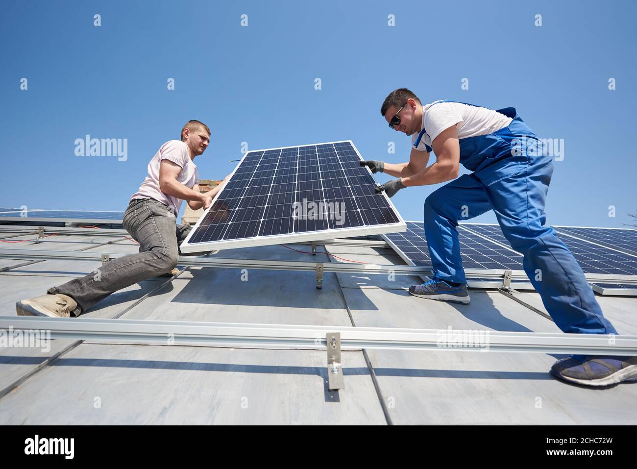 Male team workers installing stand-alone solar photovoltaic panel ...