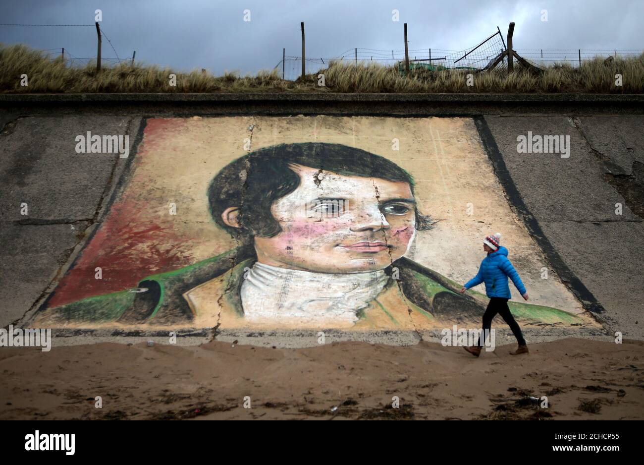A person walks past a mural of Robert Burns on the sea wall at Ardeer ...