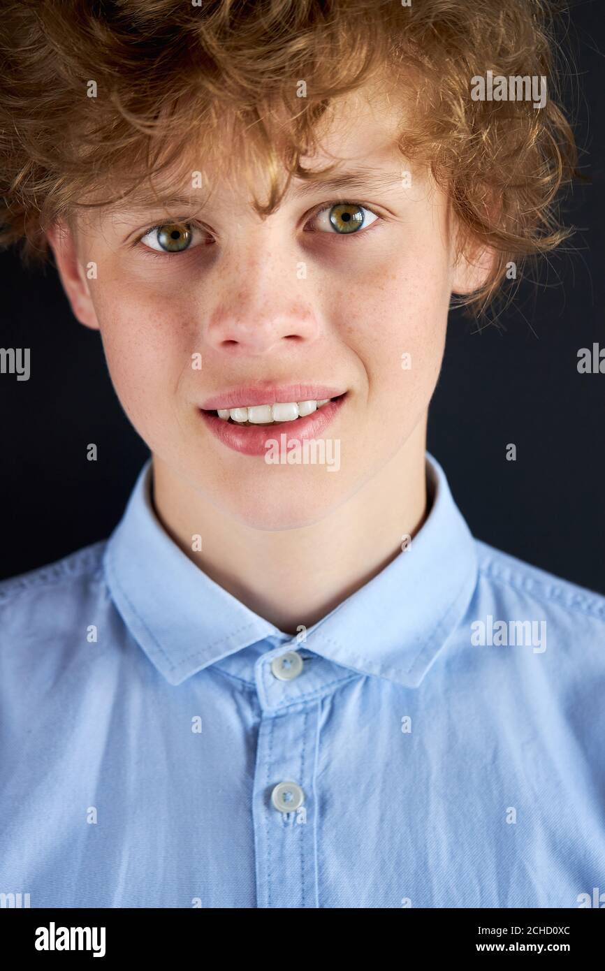 portrait of calm caucasian boy looking at camera, male teenager in blue ...