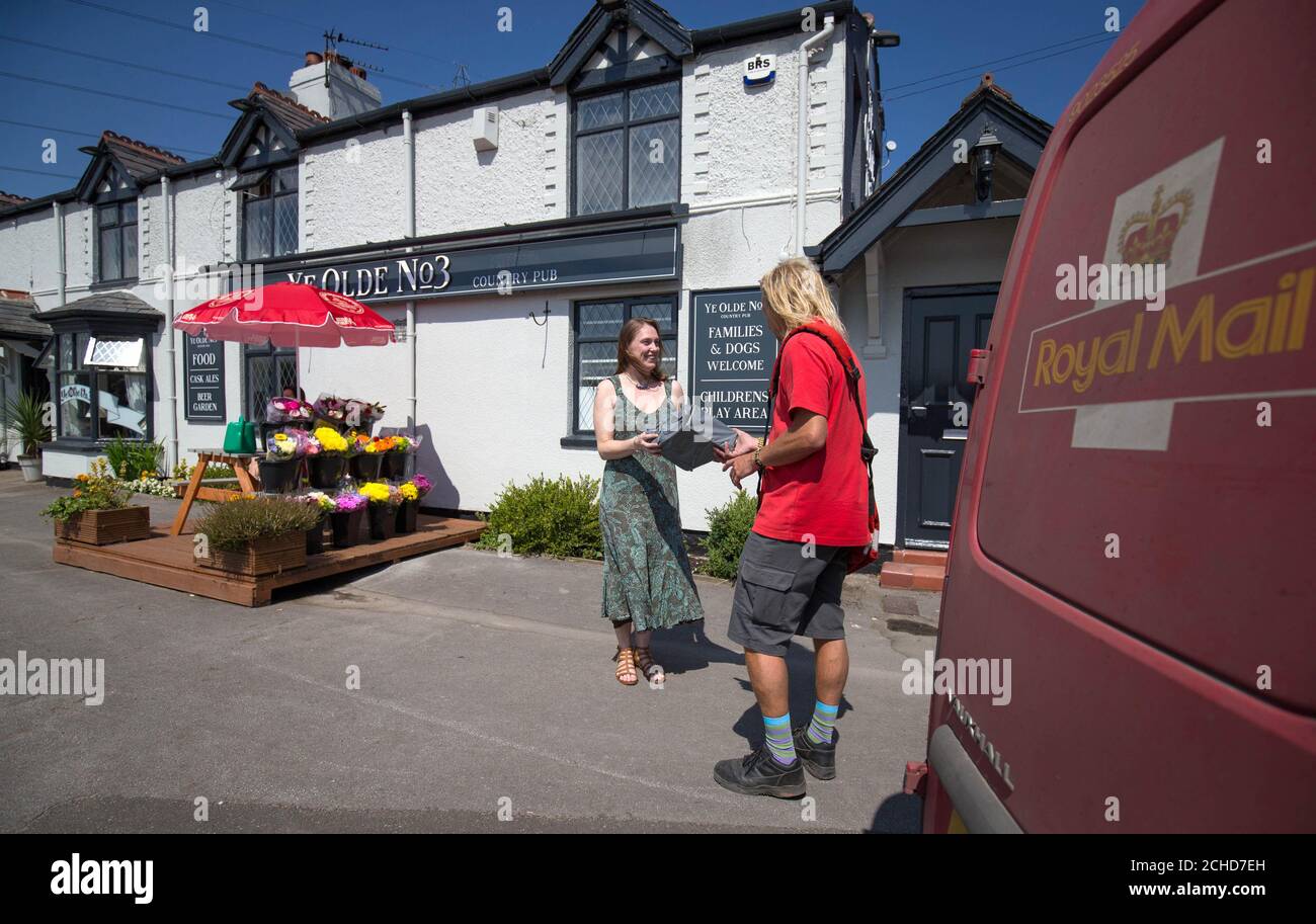 EDITORIAL USE ONLY Landlady, Amanda Watkinson, greets her local postman ...