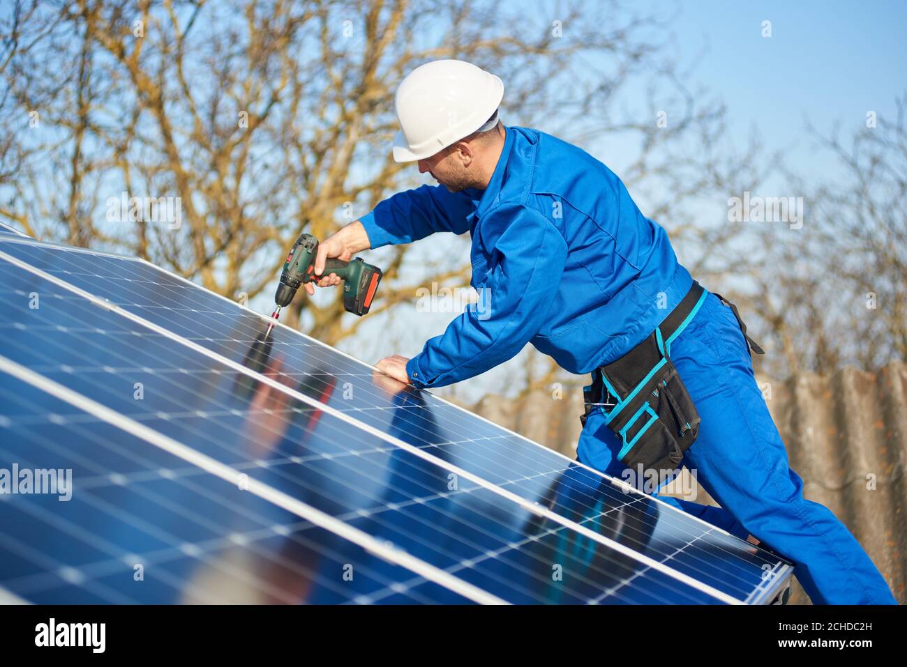 Male engineer in blue suit and protective helmet installing solar ...