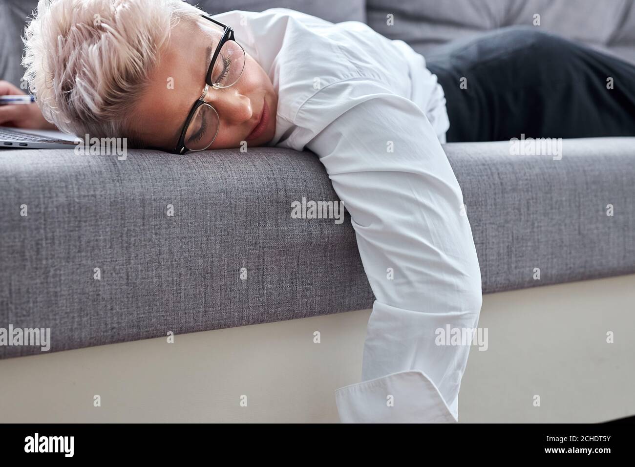 tired teacher is sleeping on sofa during online lesson, she is ...