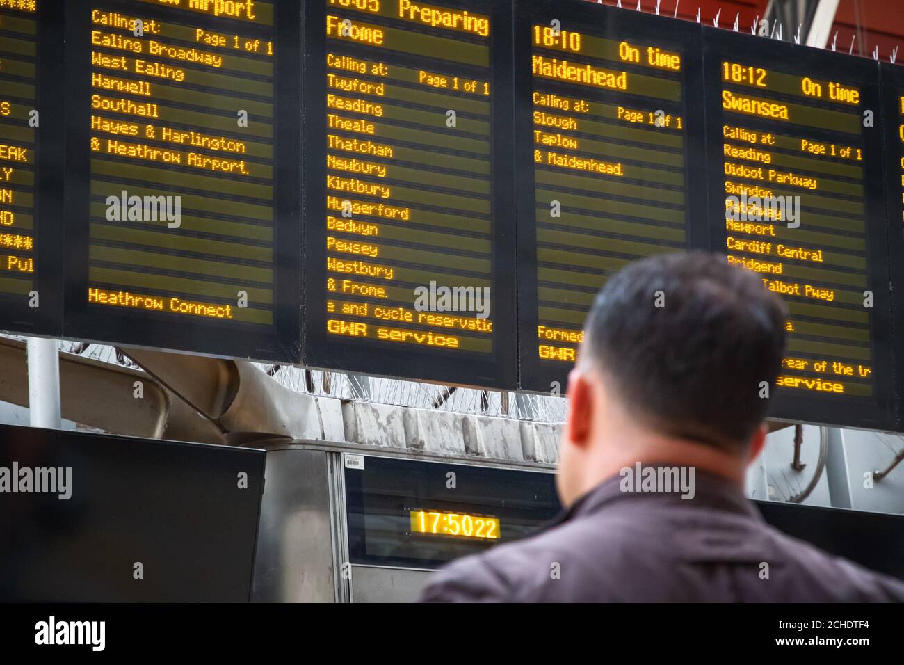 Back view of a passenger checking train timetable at London Paddington ...