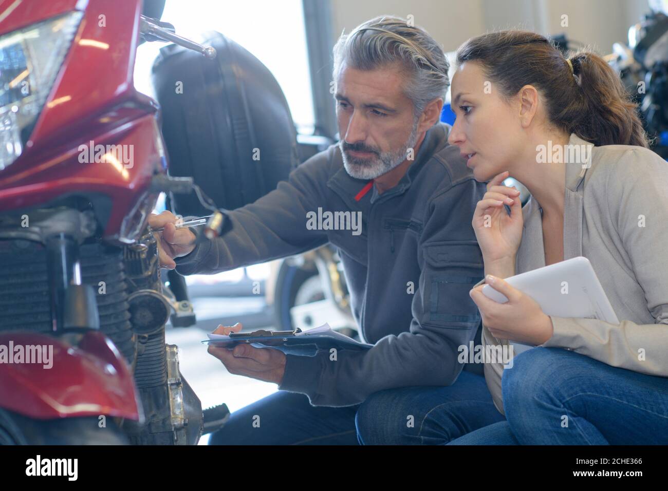 a couple checking the motorbike engine Stock Photo - Alamy