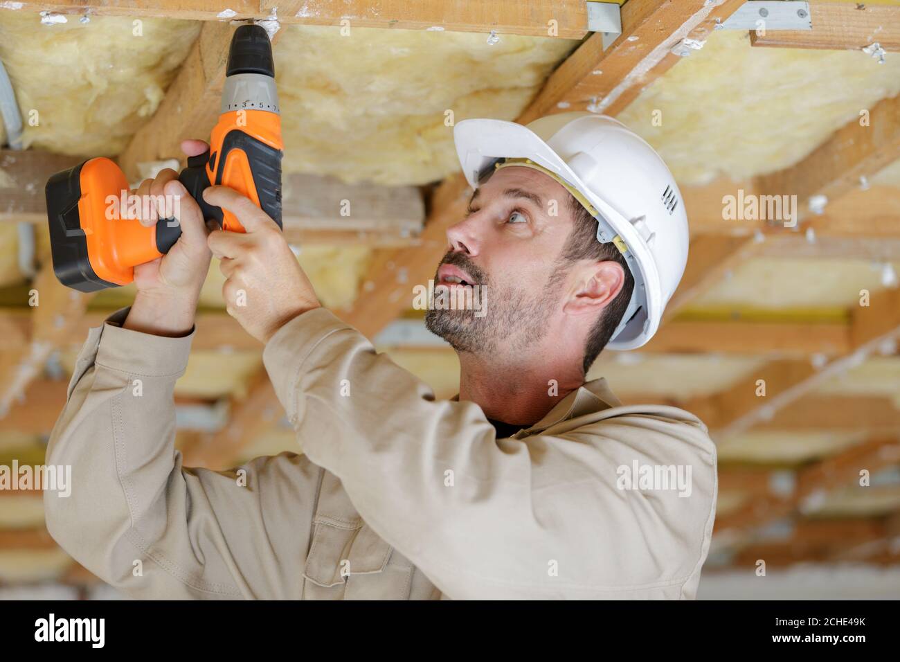 builder using cordless drill on wooden ceiling joist Stock Photo - Alamy